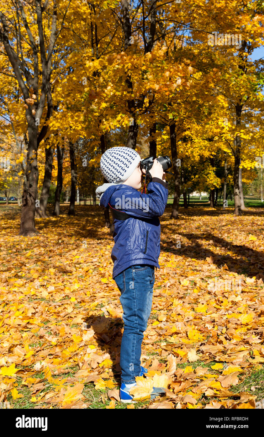 a boy in a blue jacket takes pictures of the features of the autumn ...