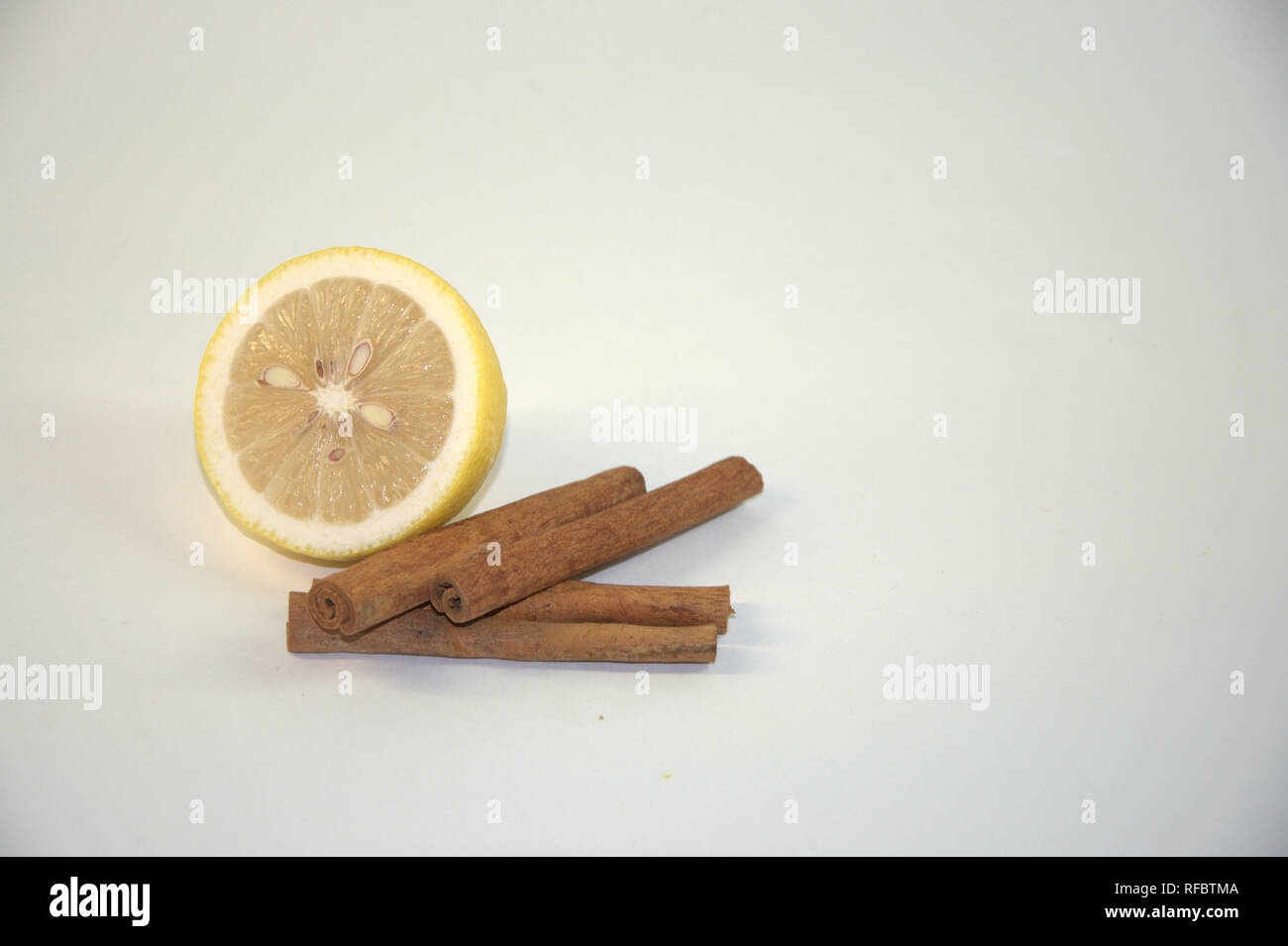 Ripe lemon and cinnamon pods in a closeup on a white background ...