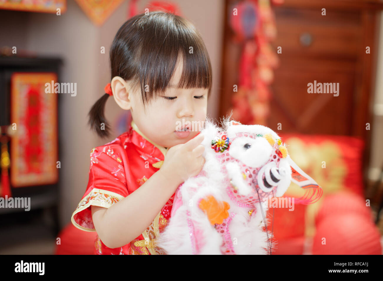 Chinese baby girl traditional dressing up holding a dance loin toy with ...