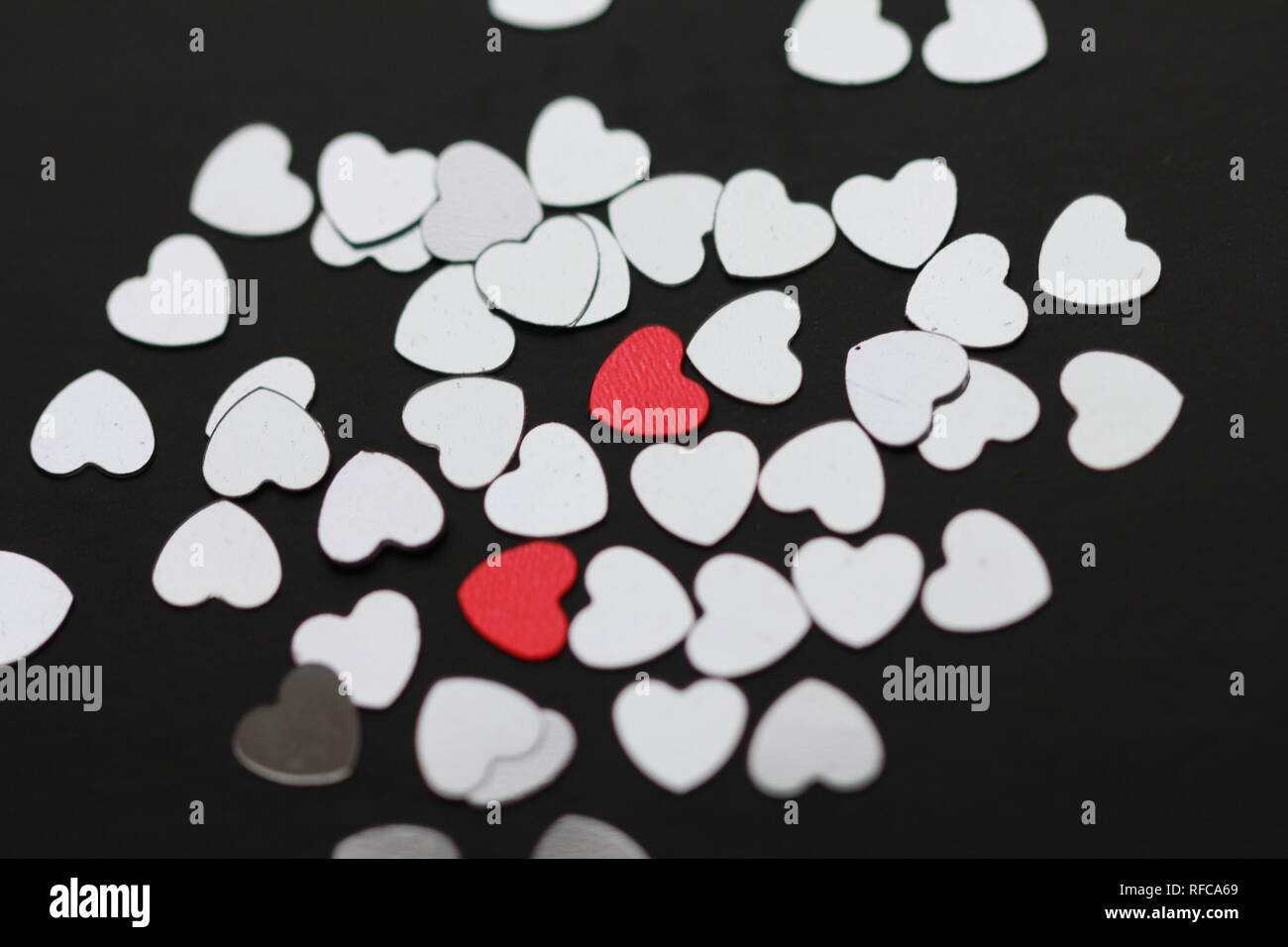 Many little metallic love herts and two red love hearts on black ...