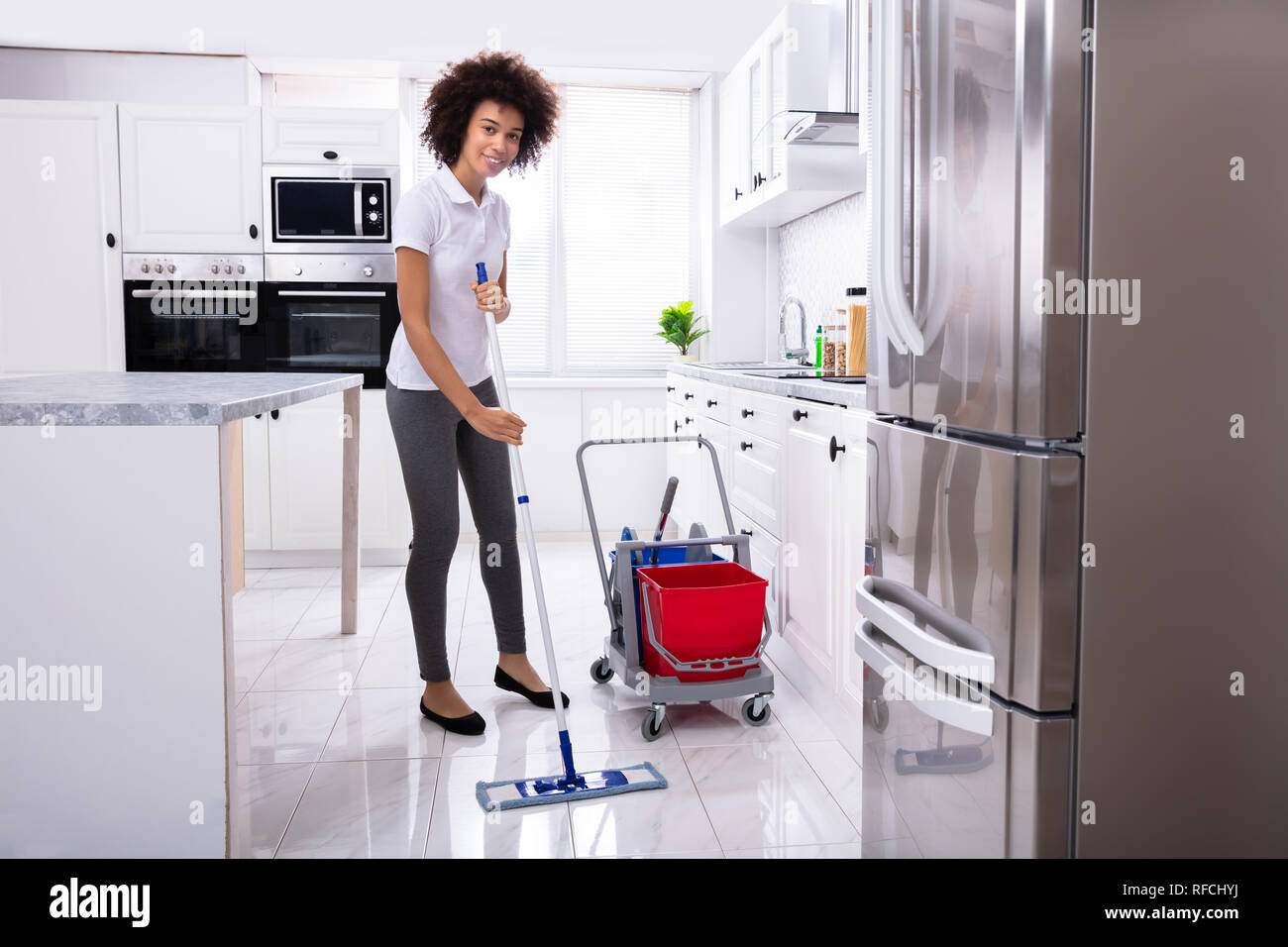 Female Janitor Cleaning The White Floor With Mop In Modern Kitchen ...