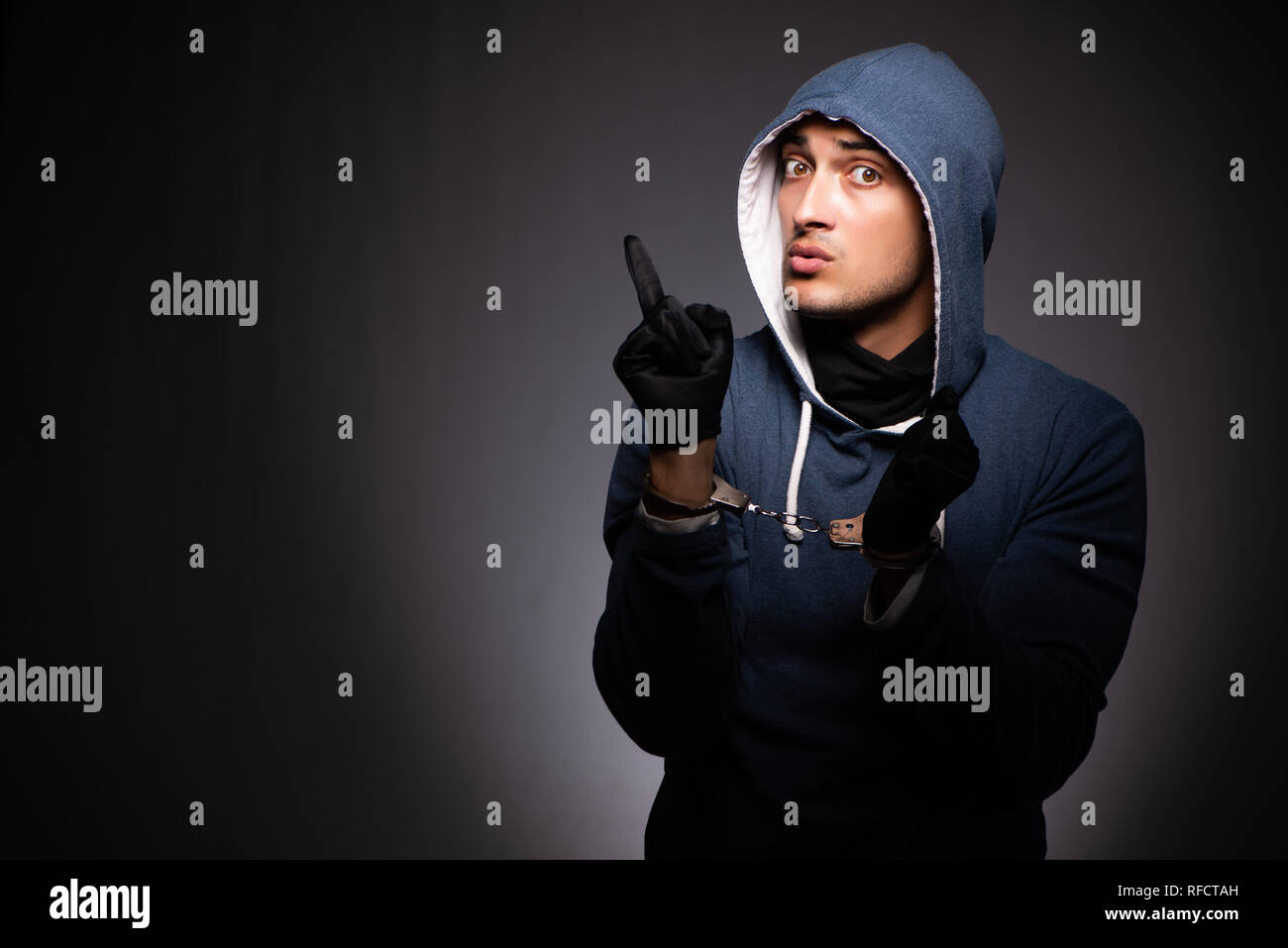 Young gangster in hood on grey background Stock Photo - Alamy