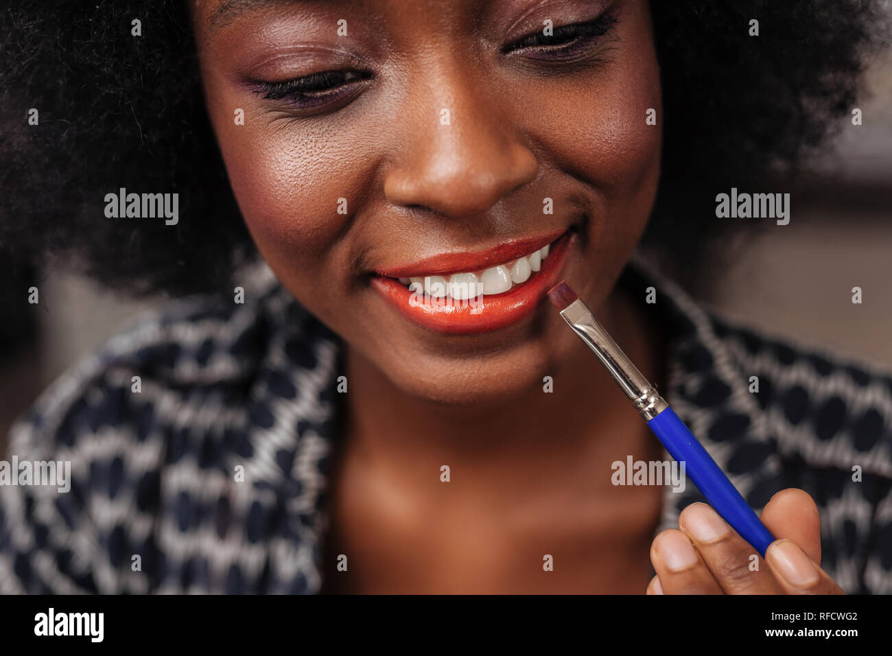Amazing african american woman with curly hair trying a new lipstick ...