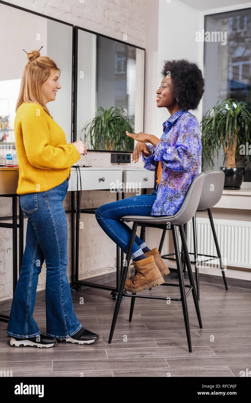 Beautiful dark-skinned stylist in beige boots talking to a client Stock ...