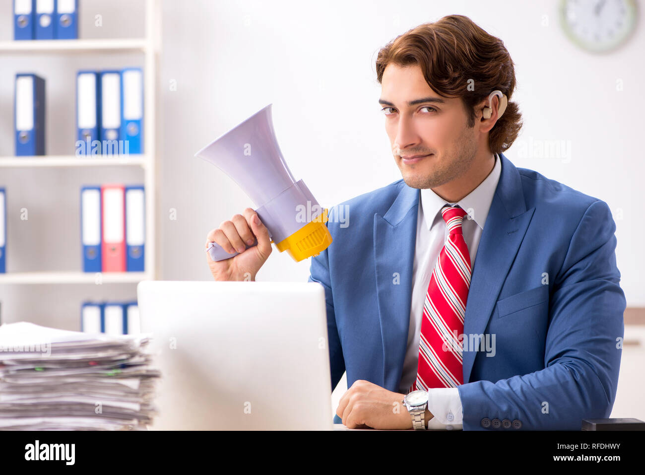 Deaf employee using hearing aid in office Stock Photo - Alamy