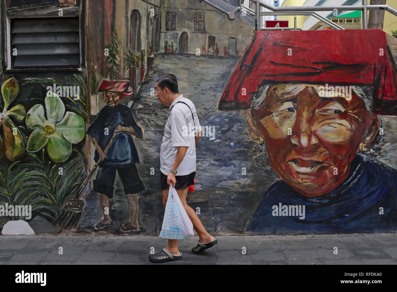 A man passing a wall painting in Chinatown, Singapore, depicting a so ...