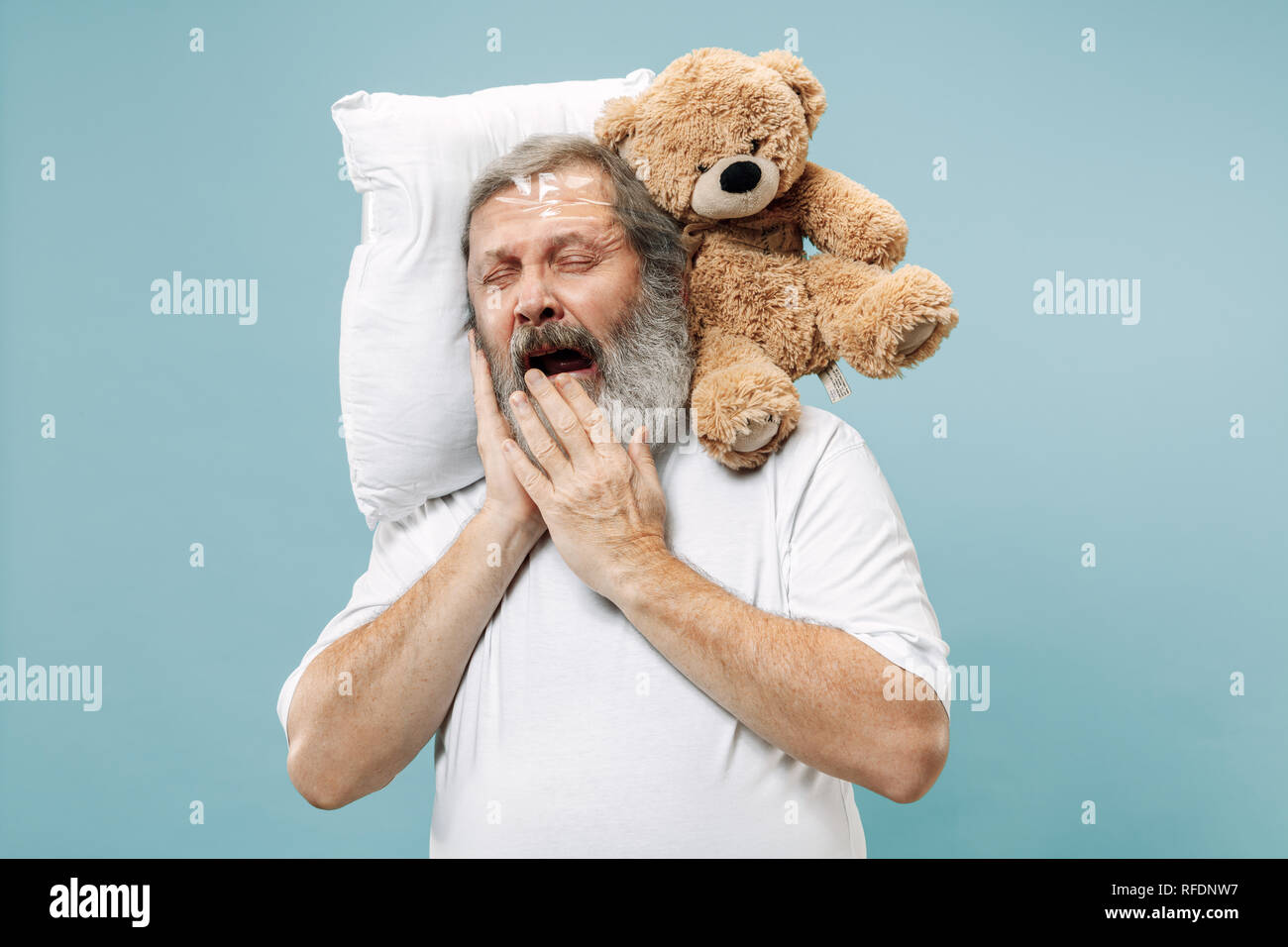 Tired man sleeping at home or office having too much work. Bored businessman with pillow and toy ...