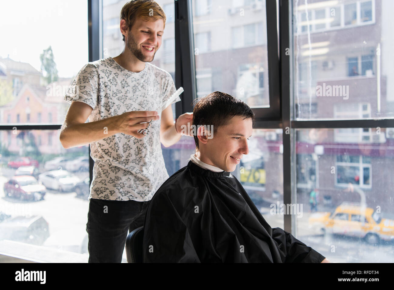 hairdresser does hair with comb of handsome satisfied client in ...