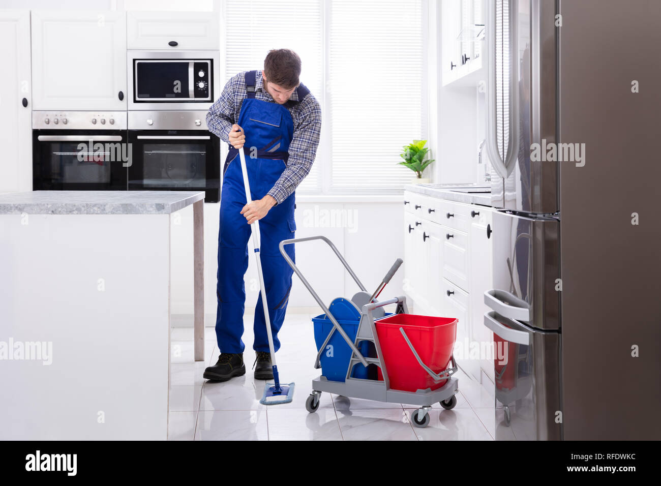 Male Janitor Cleaning Floor With Mop In Kitchen Stock Photo - Alamy