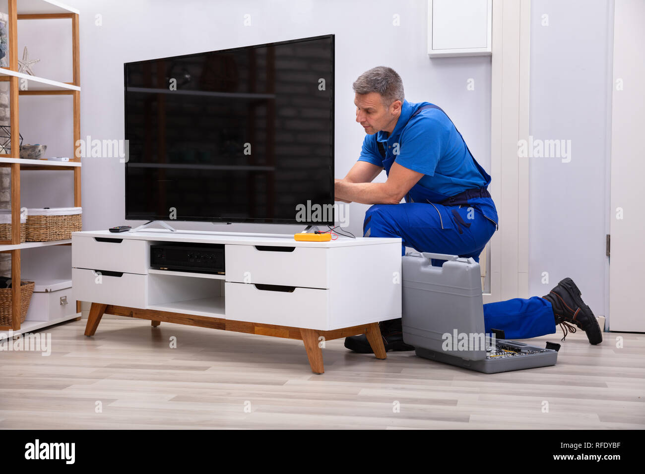 Male Technician Repairing Television With Digital Multimeter At Home ...
