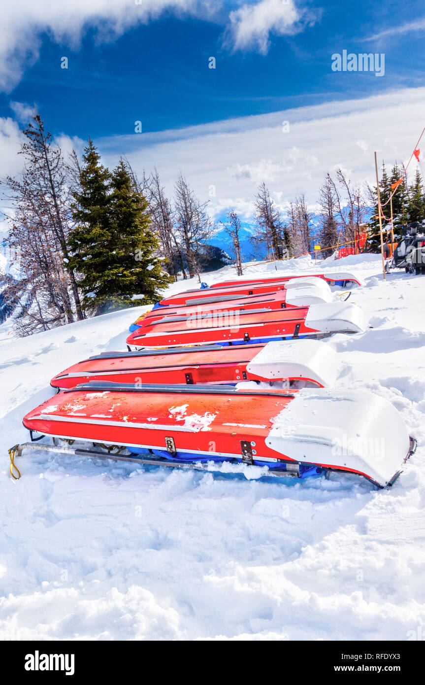 Rows of ski patrol toboggans or rescue sleds lie on snow on mountain ...