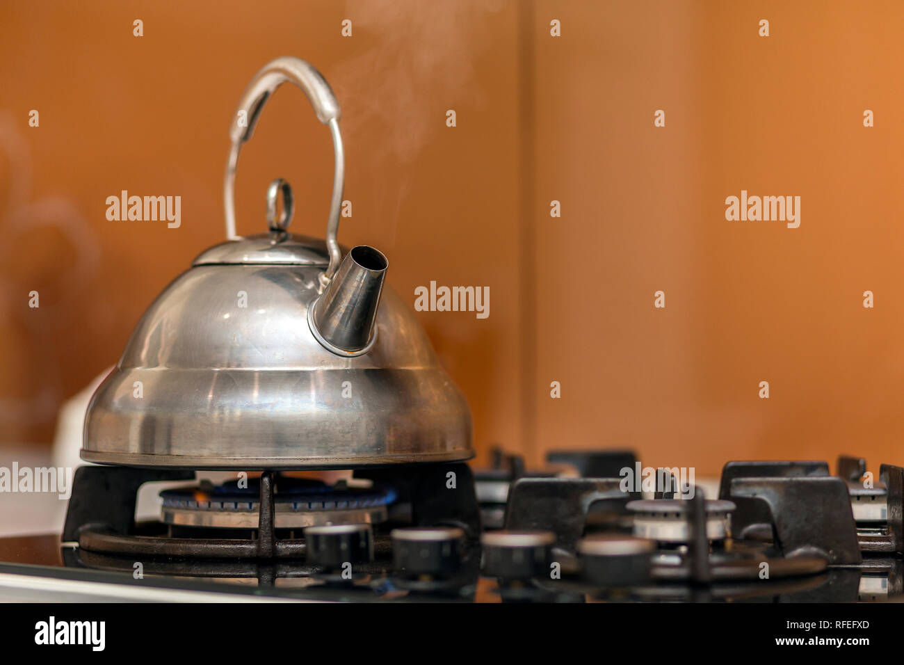 Shiny stainless tea kettle teapot with boiling water on gas stove on ...