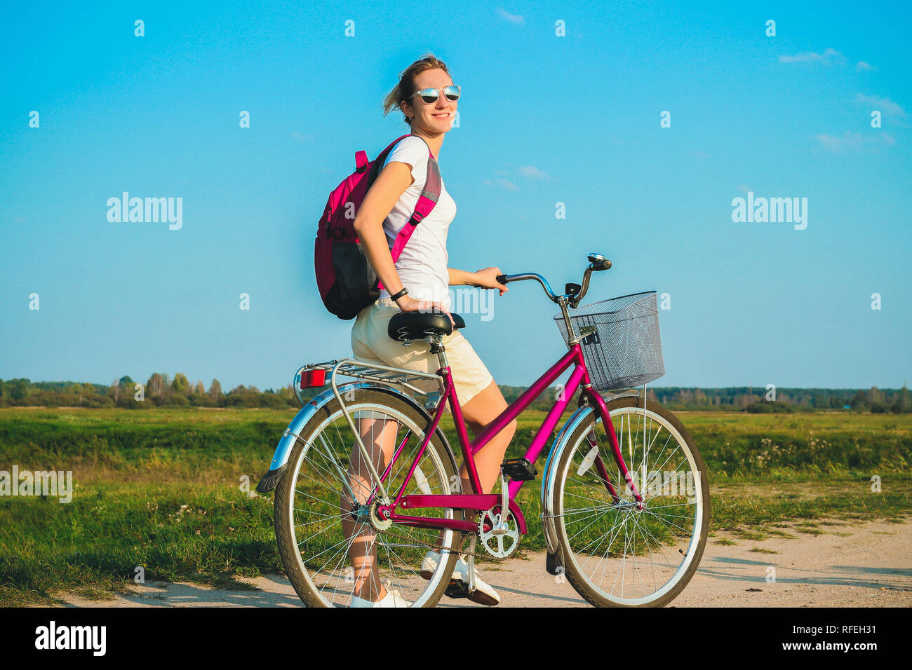 Young beautiful woman rides on a bicycle in the summertime on the green ...