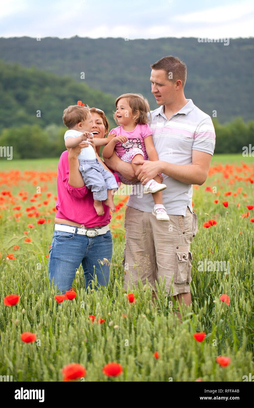 Family in poppy field having fun Stock Photo - Alamy