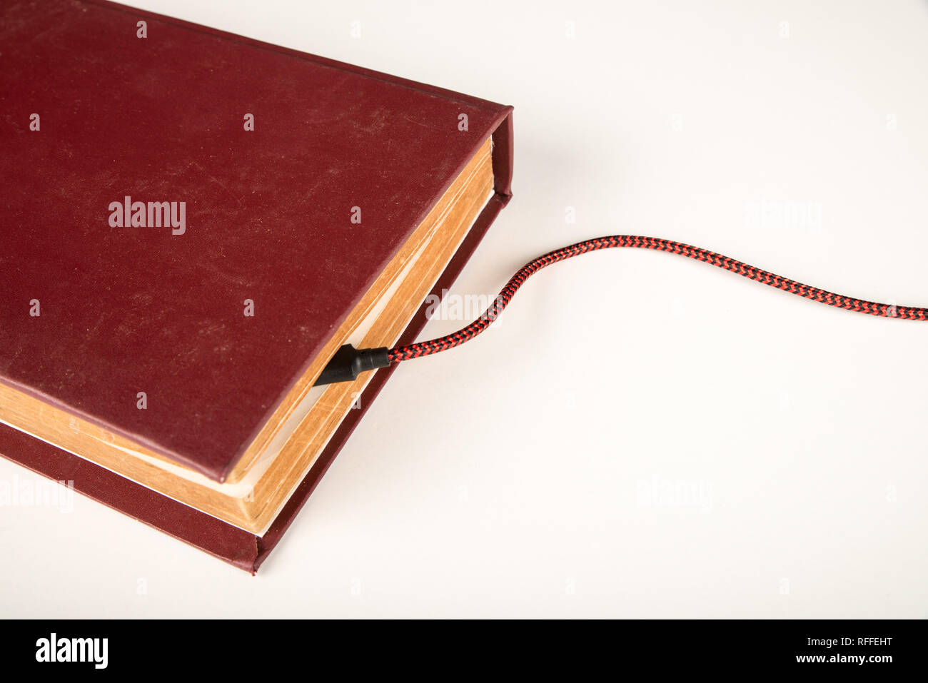 Old book with a battery charging cable, a concept of analog versus ...