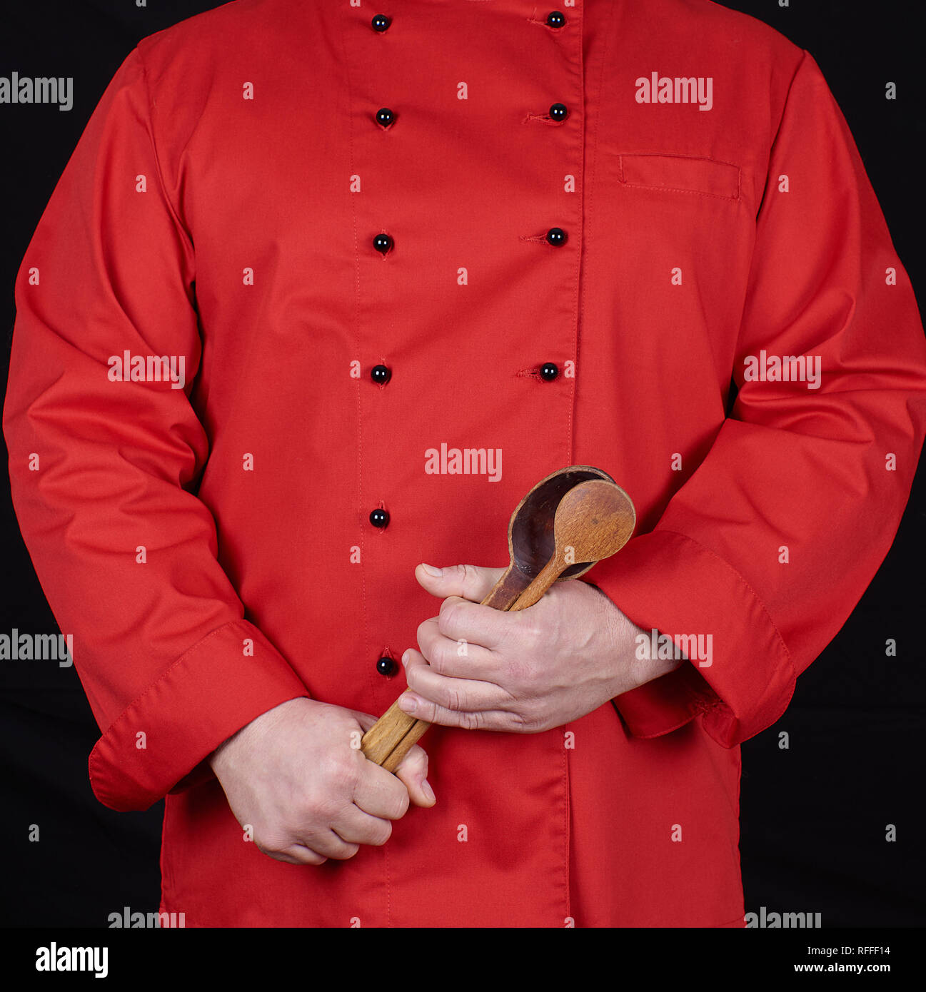 chef in red uniform holding old wooden spoons, black background Stock ...