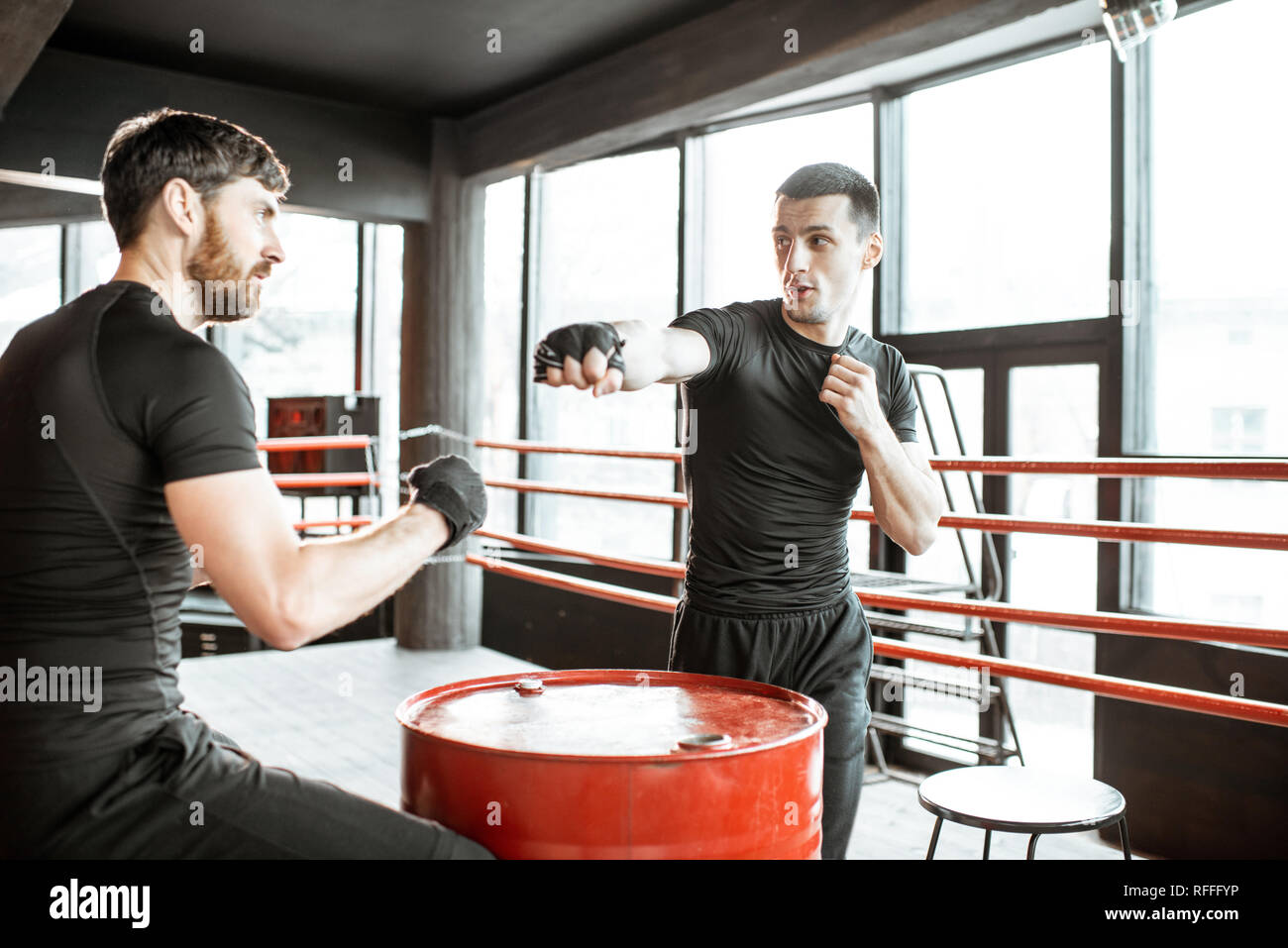 Boxing trainer showing to a man how to fight, teaching to box in the ...