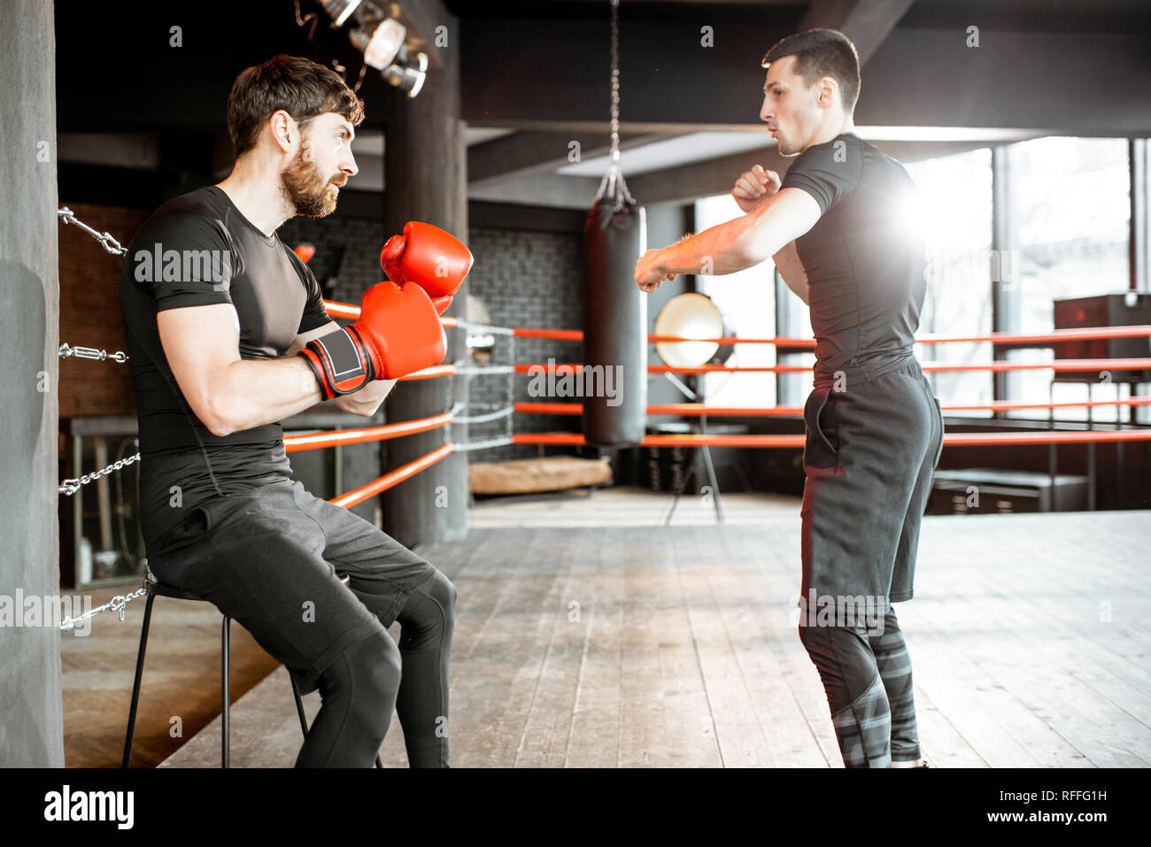 Boxing trainer showing to a man how to fight, teaching to box in the ...
