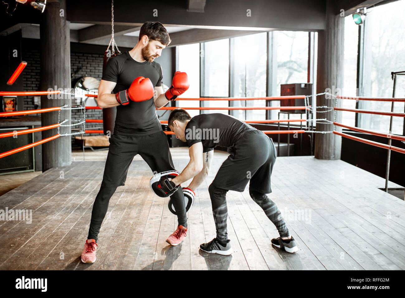 Boxing trainer showing to a man how to fight, teaching to box on the ...