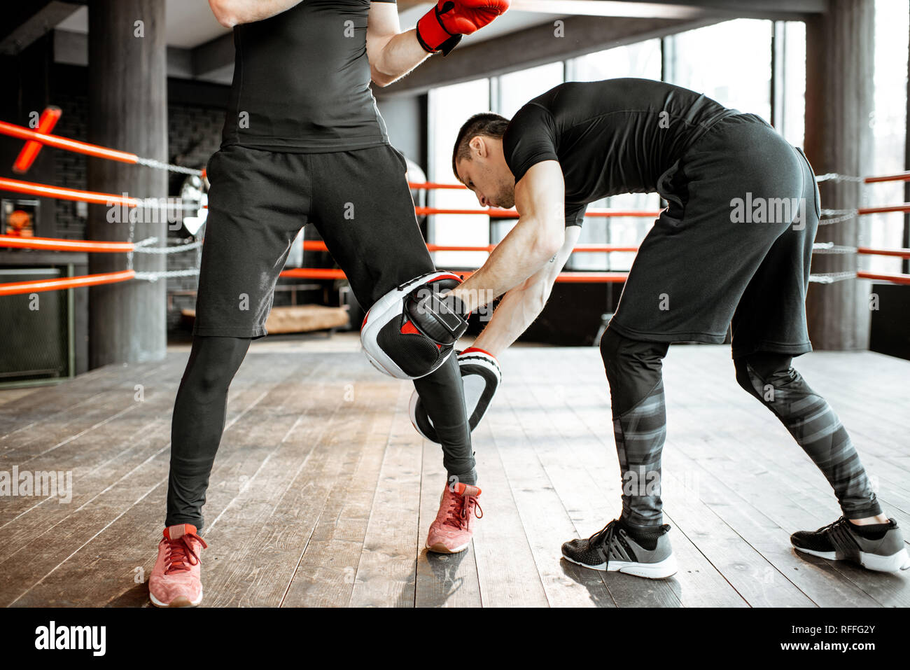 Boxing trainer keeping leg of a man learning how to fight correctly on ...