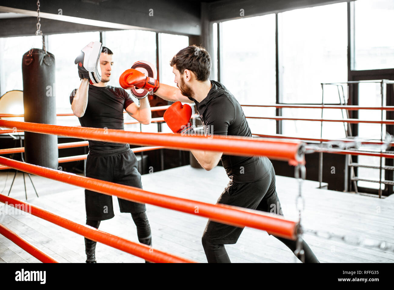 Athletic man fighting during the training with boxing trainer on the ...