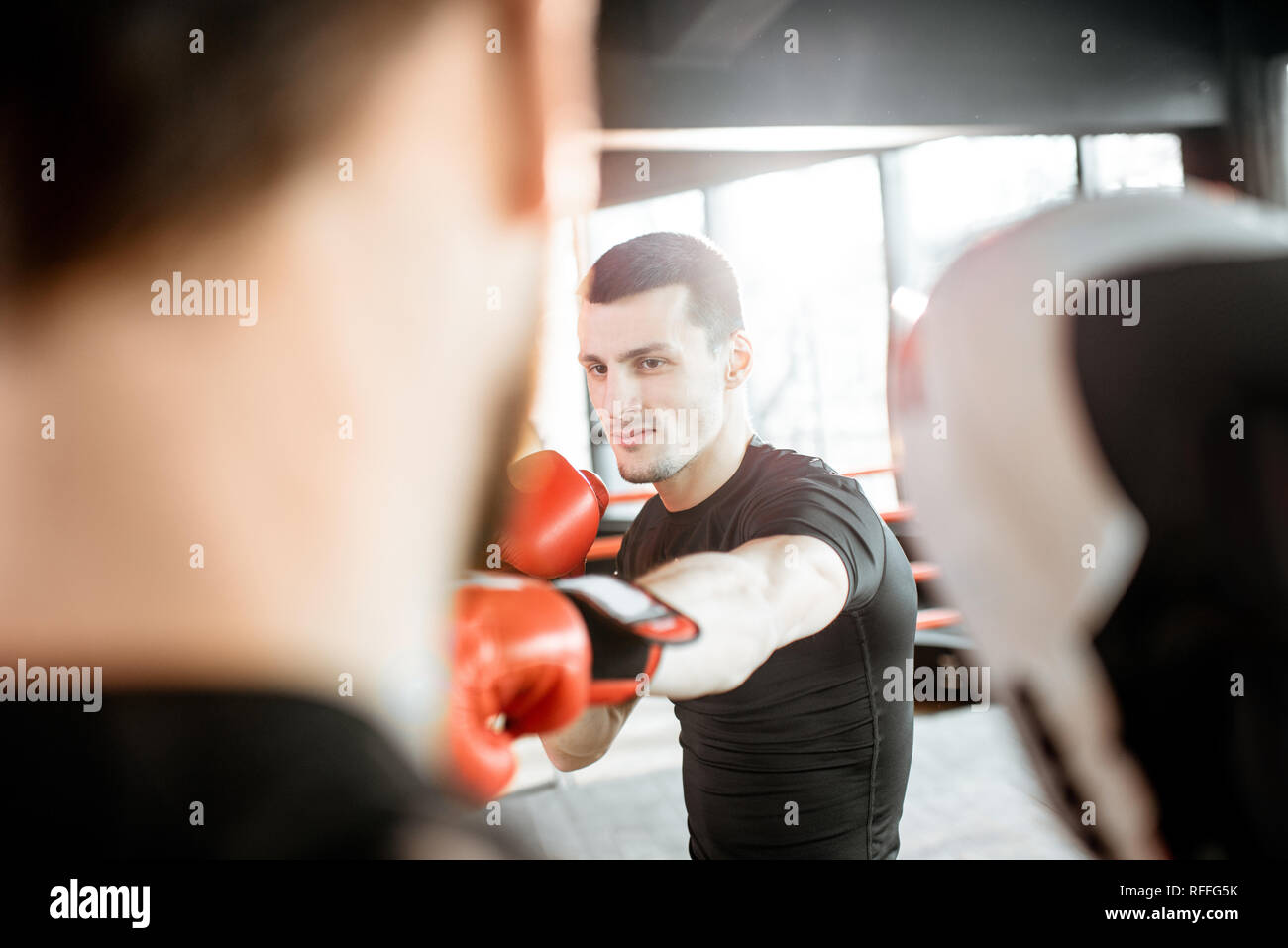 Athletic man fighting during the training with boxing trainer on the ...
