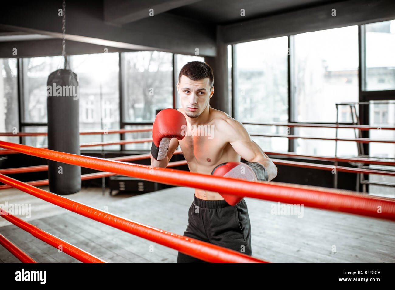 Young athletic man hard training to box, fighting on the boxing ring at ...