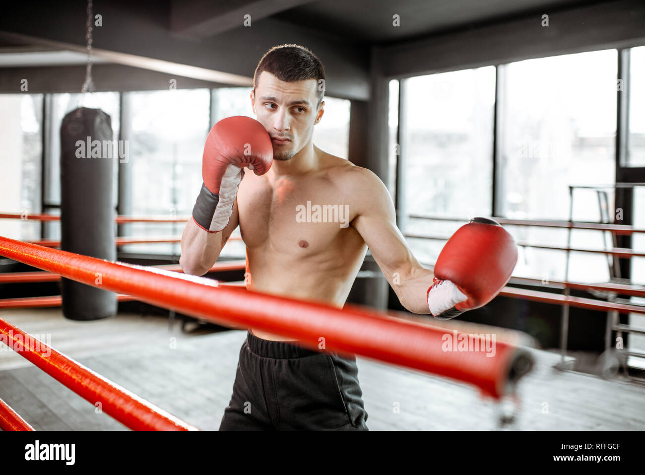 Young athletic man hard training to box, fighting on the boxing ring at ...