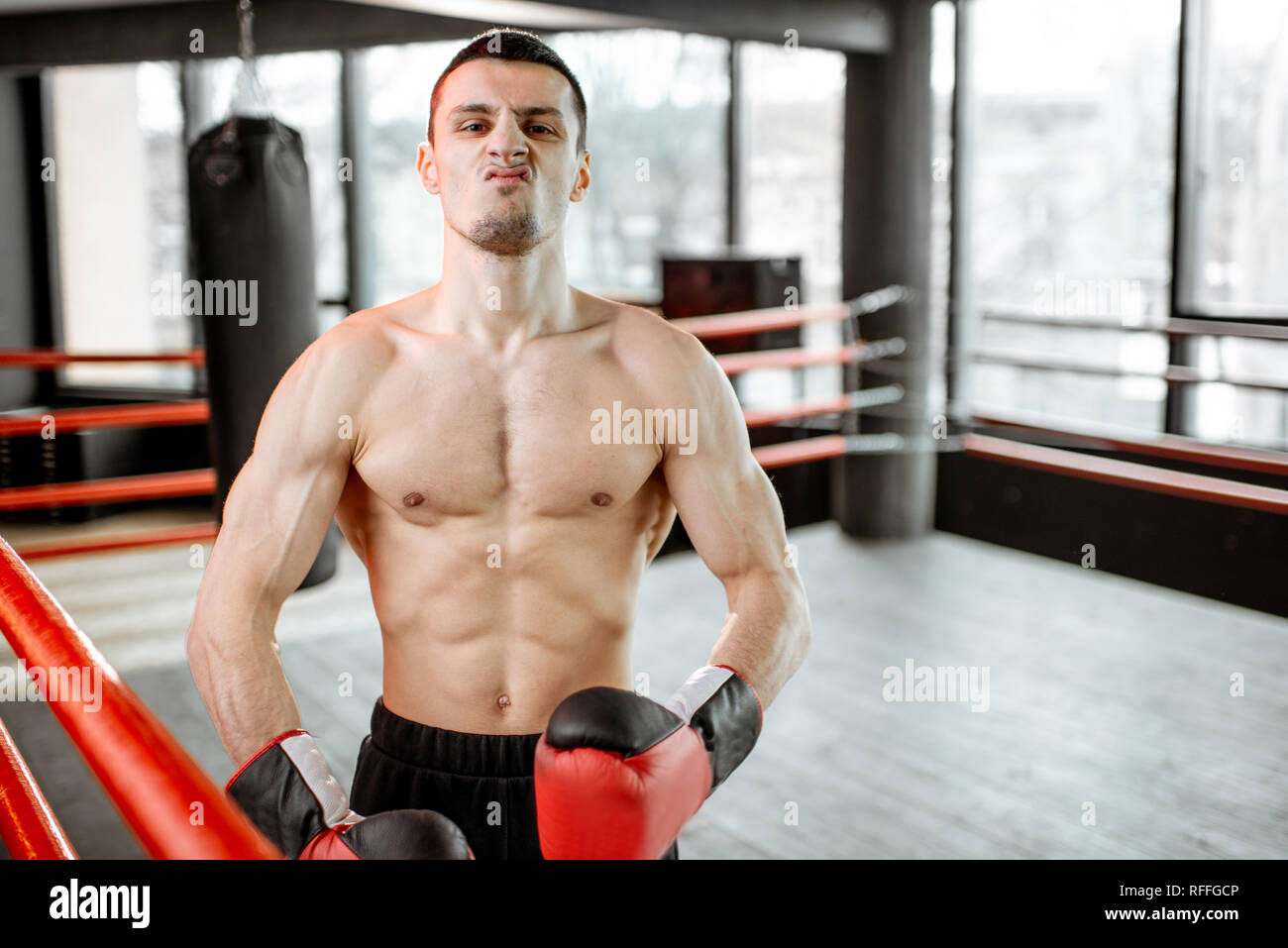 Portrait of a strong boxer showing muscles during the training on the ...