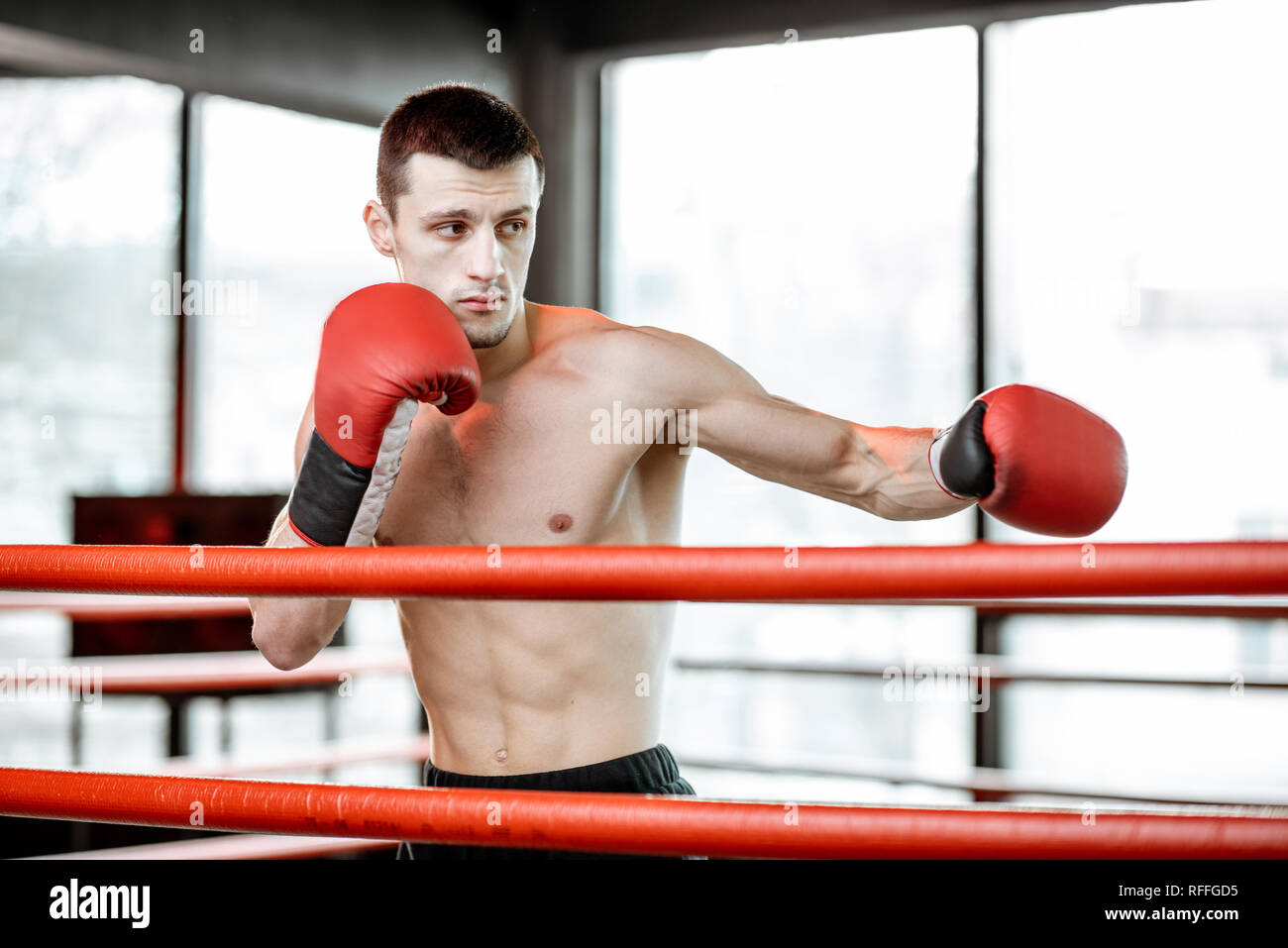 Young athletic man hard training to box, fighting on the boxing ring at ...