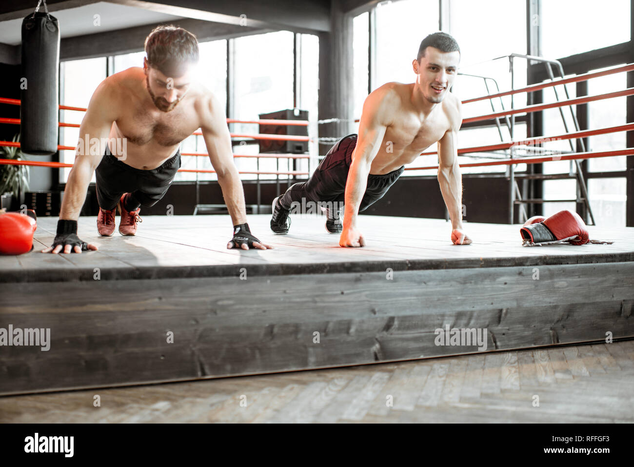 Two athletic men doing push-ups on the boxing ring, training before ...