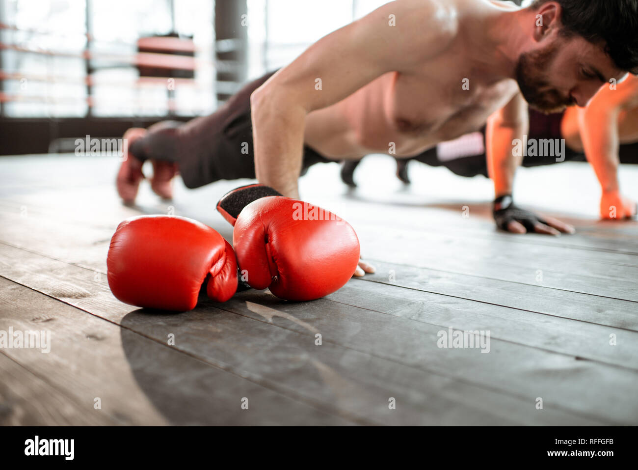 Two athletic men doing push-ups on the boxing ring, training before ...