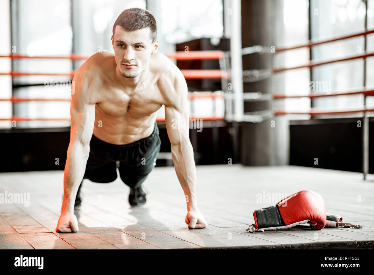 Portrait of a strong boxer showing muscles during the training on the ...