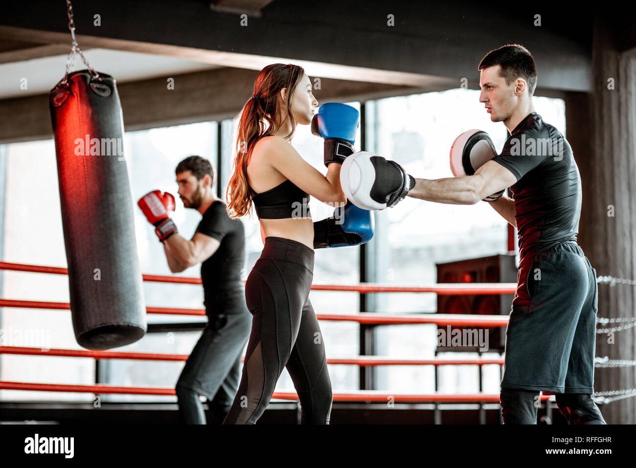 Young woman training to box with personal coach on the boxing ring at ...