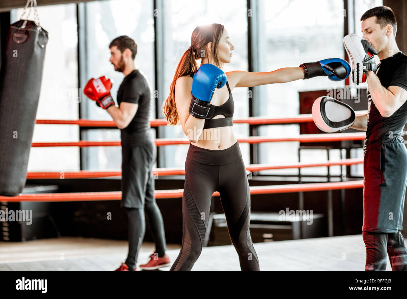 Young woman training to box with personal coach on the boxing ring at ...