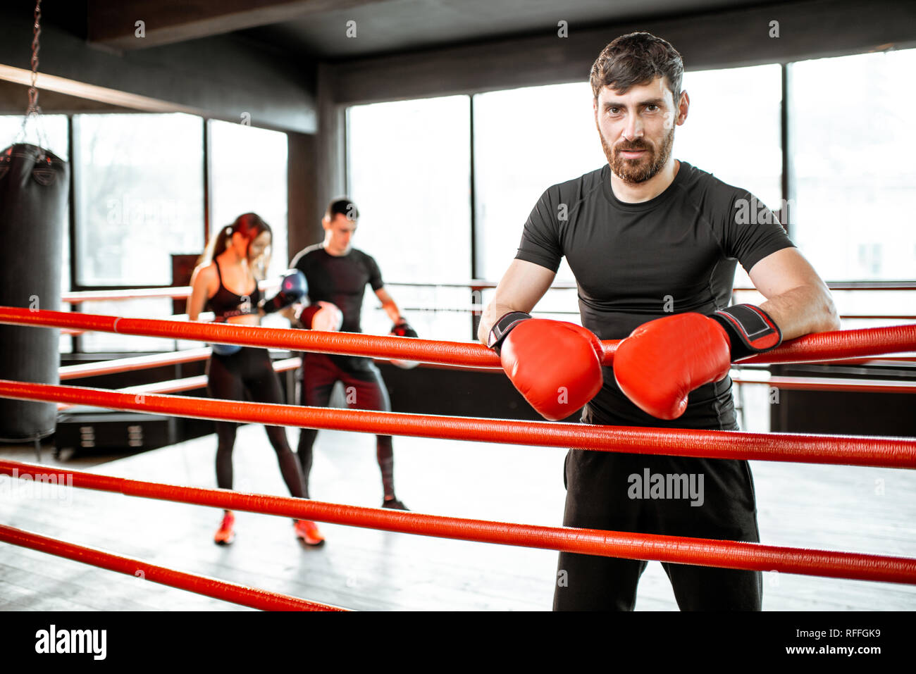 Man resting after the training on the boxing ring with people on the ...