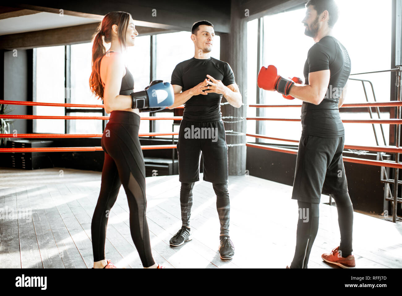 Man and woman training to box with personal coach on the boxing ring at ...