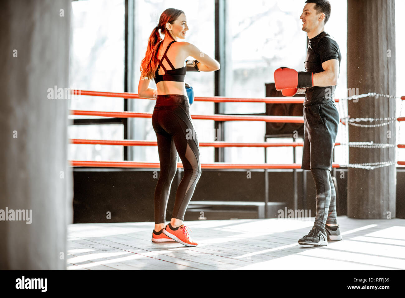 Young woman training to box with personal coach on the boxing ring at ...