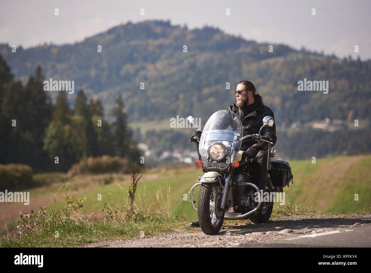 Handsome bearded motorcyclist with long hair in black leather jacket ...