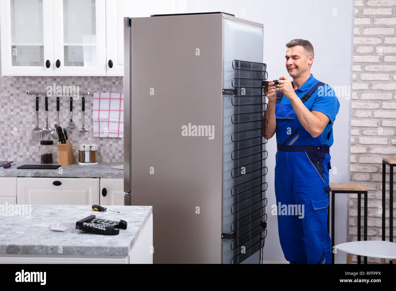 Electrician working on fridge in home hi-res stock photography and ...