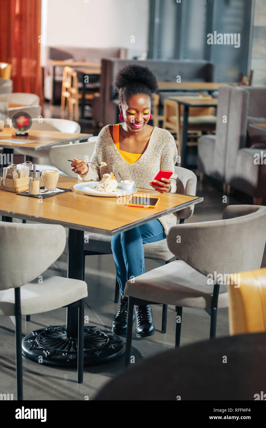 Dark-haired woman wearing jeans and light sweater sitting in cafeteria ...