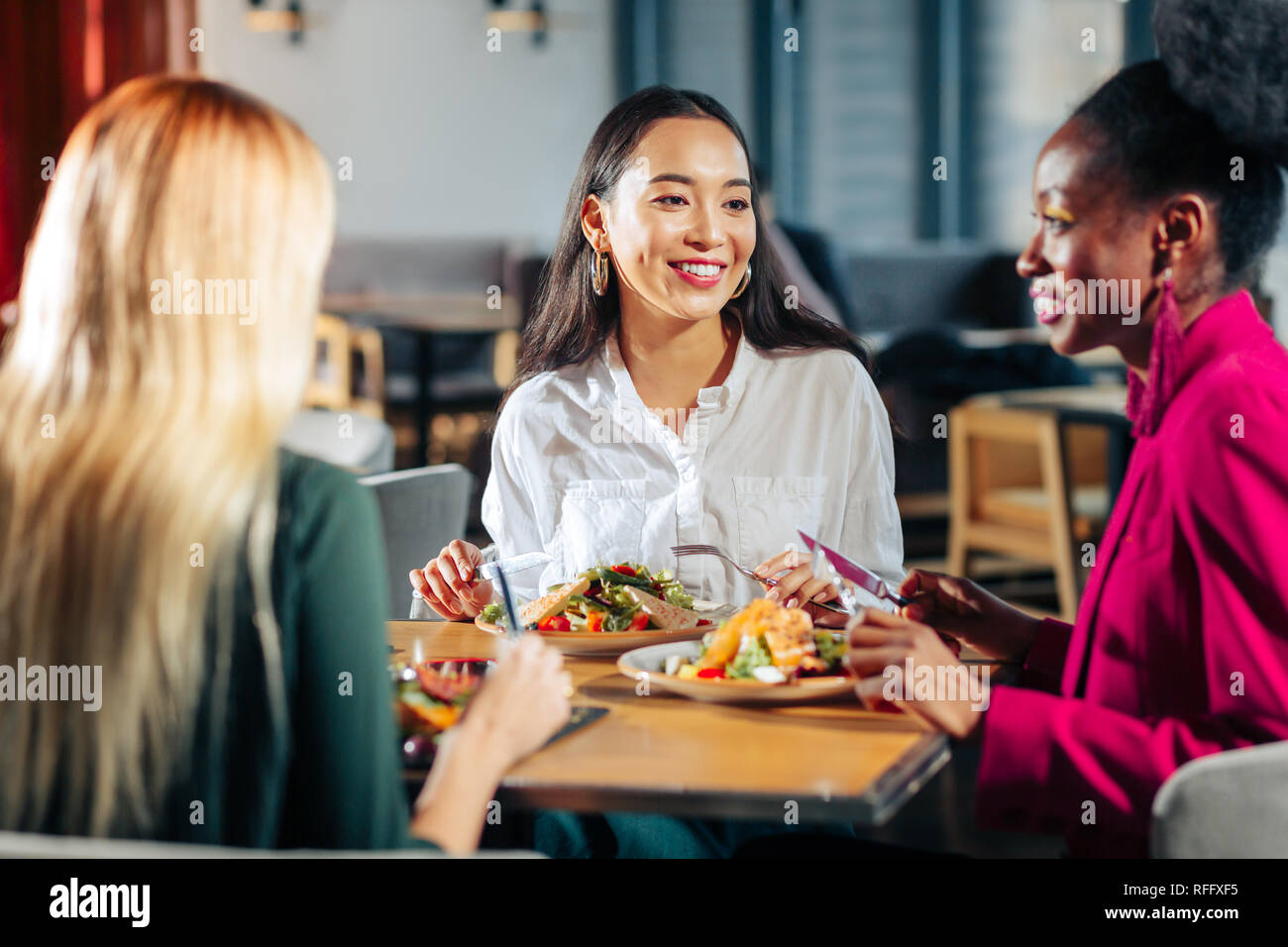 Three friends eating delicious salads in their favorite restaurant ...