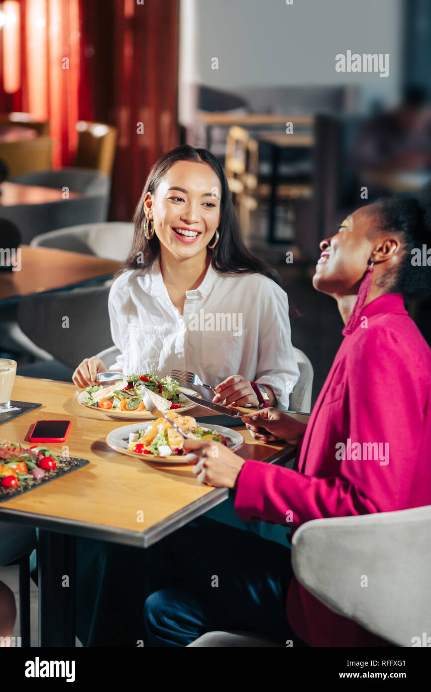 Friends laughing while communicating in a big restaurant Stock Photo ...