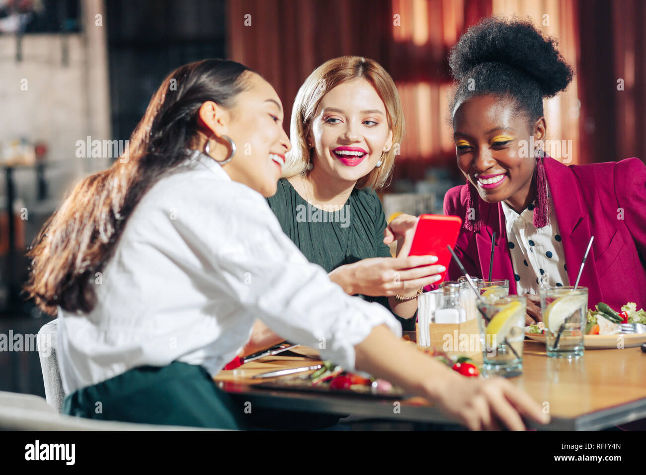 Three best friends laughing while watching their photos on phone Stock ...