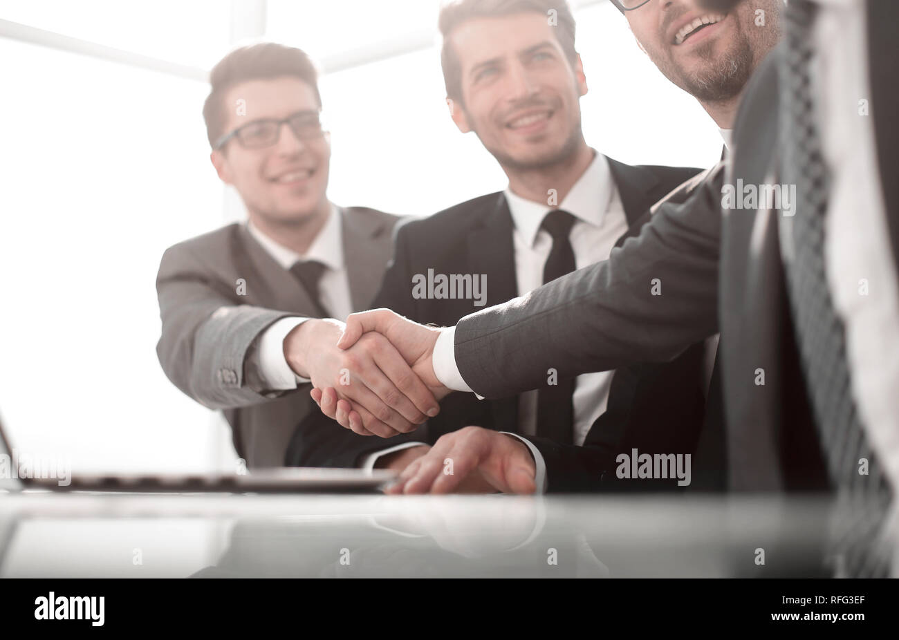 employees shaking hands sitting at the office Desk Stock Photo - Alamy