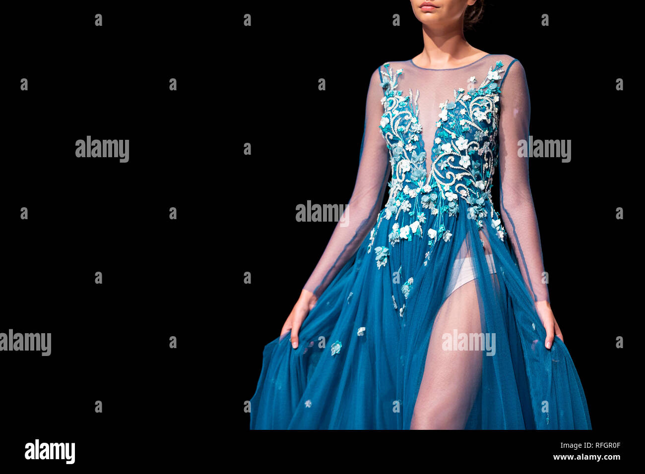 Female model walks the runway in blue dress isolated on a black ...