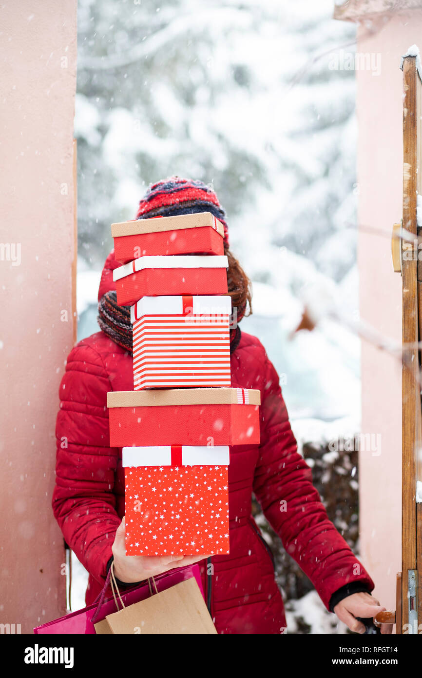 woman returning home from shopping holding pile of christmas present ...