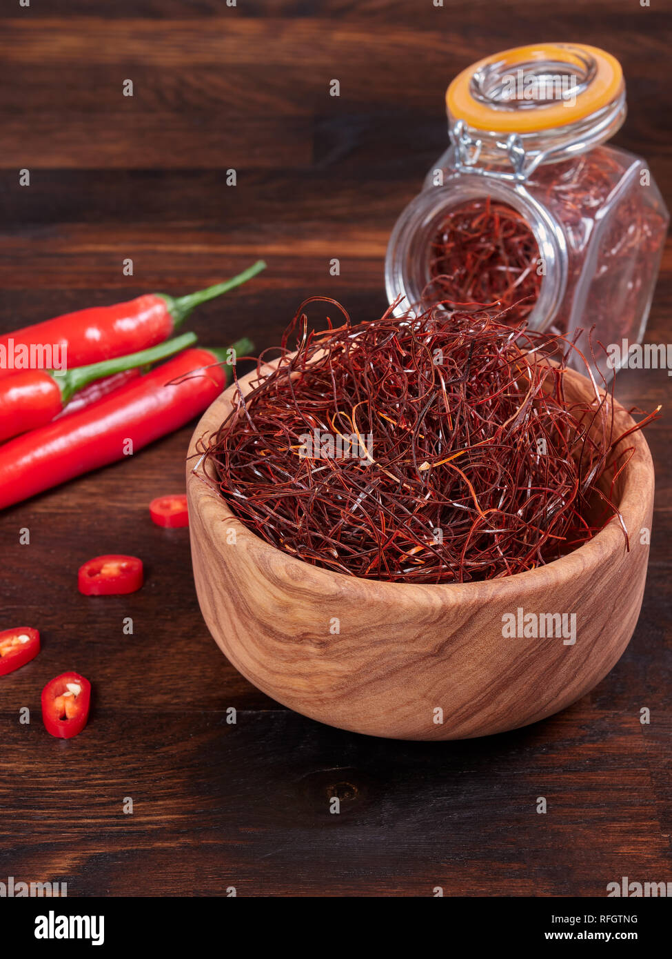 An olive wood bowl filled with thin threads of sun-dried red chili also ...