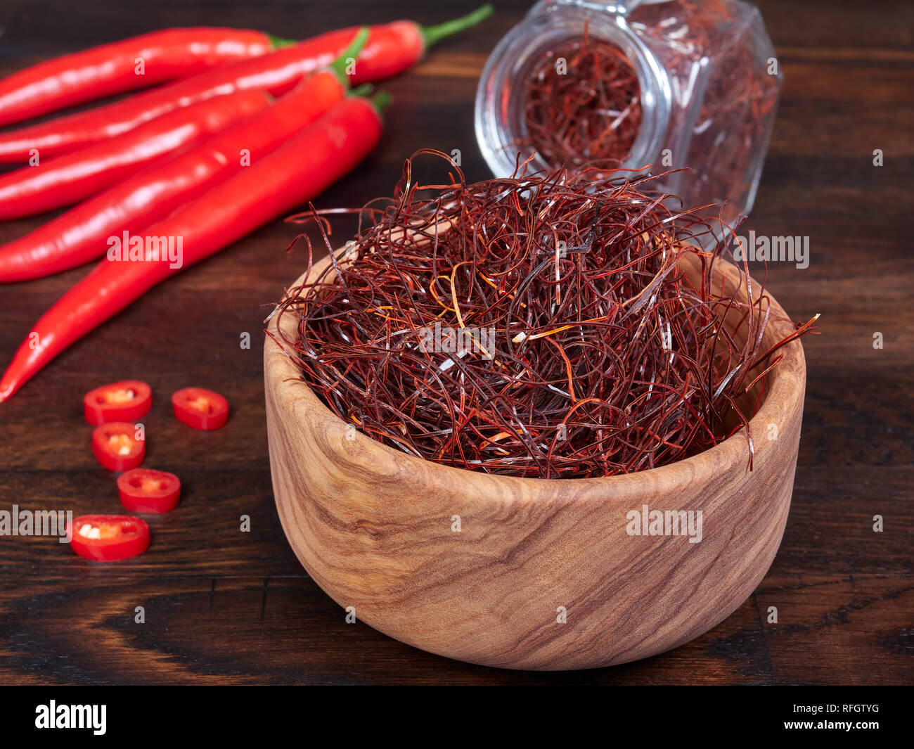 An olive wood bowl filled with thin threads of sun-dried red chili also ...