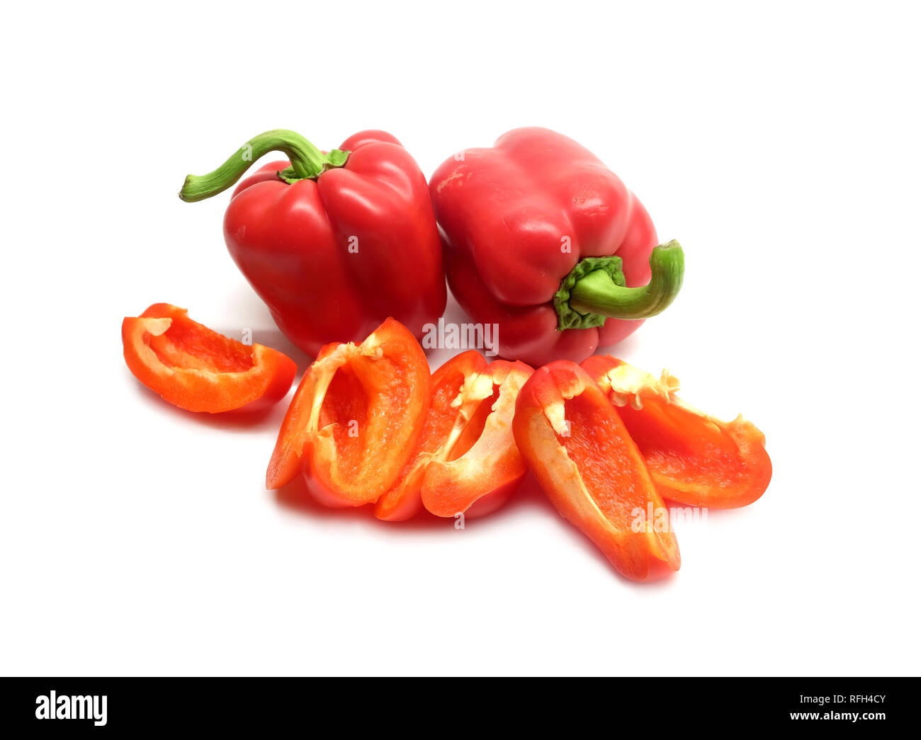 Still life with three whole and sliced red ripe bell peppers isolated ...